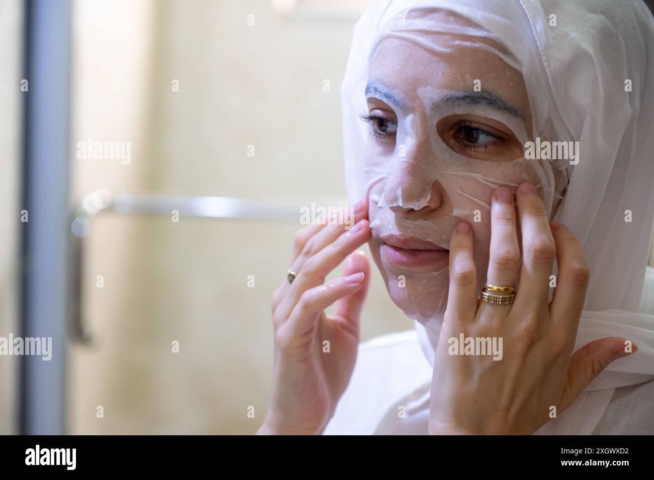 Arabic muslim female wearing hijab applying facial mask in spa or bath ...