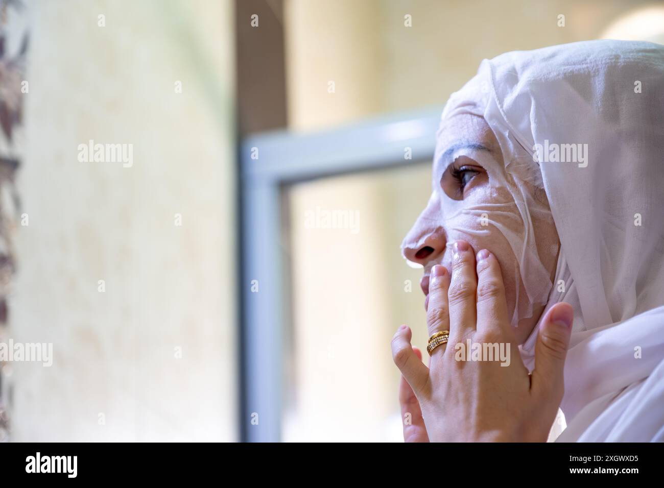 Arabic muslim female wearing hijab applying facial mask in spa or bath ...