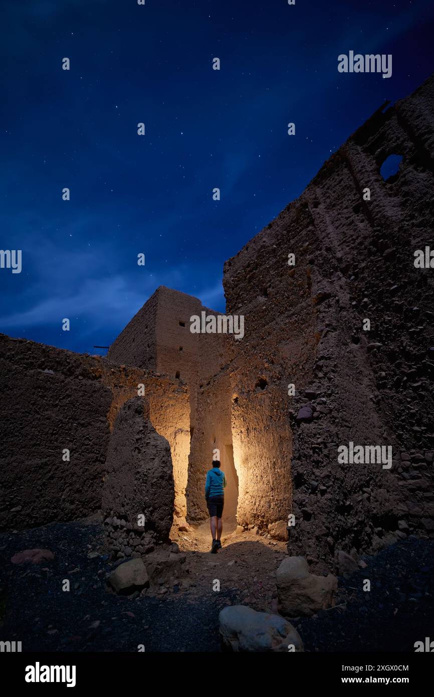 A solitary figure stands illuminated by a warm light amidst the ancient ...