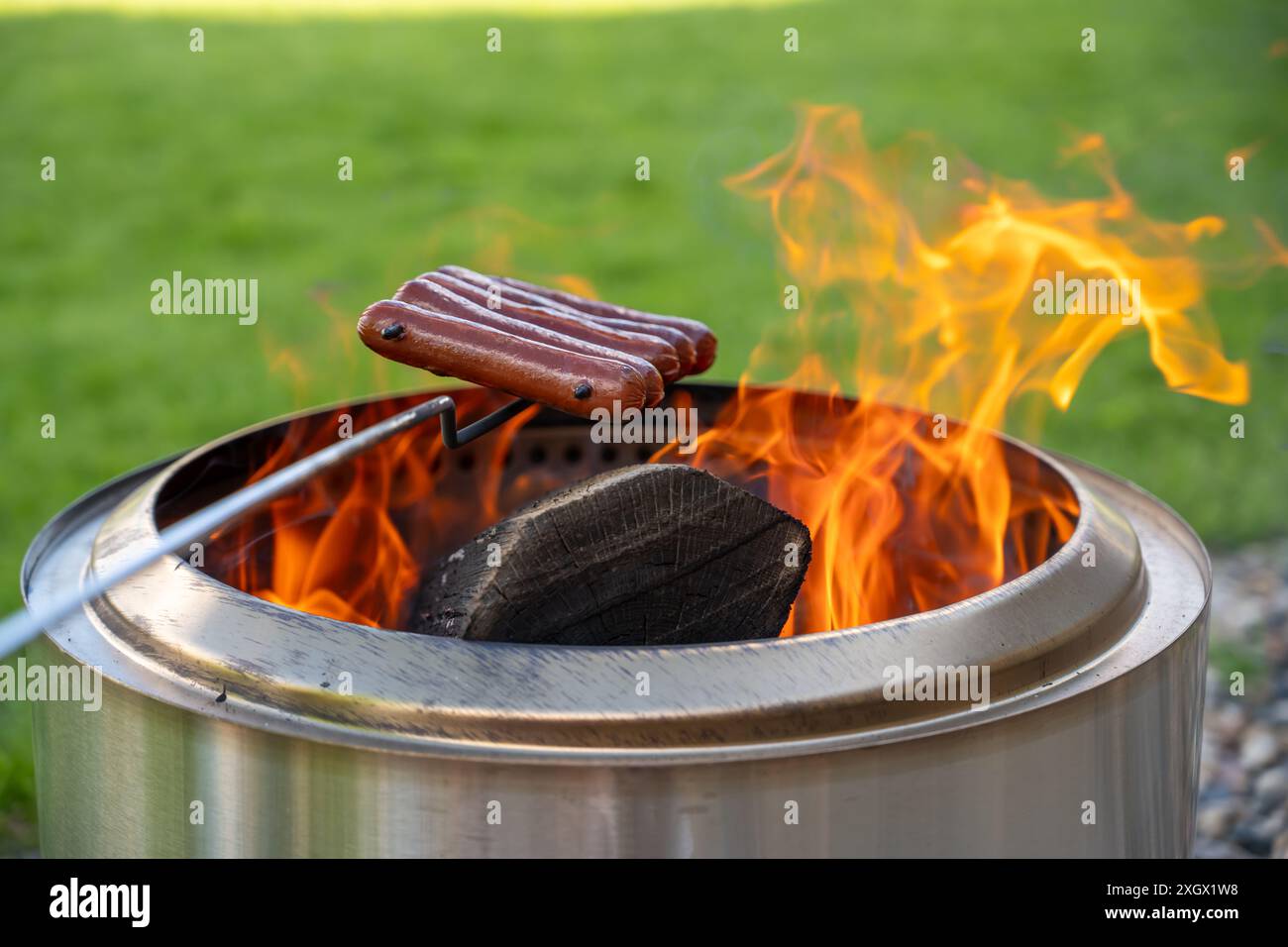 Cooking hot dogs over a stainless steel smokeless fire pit Stock Photo ...