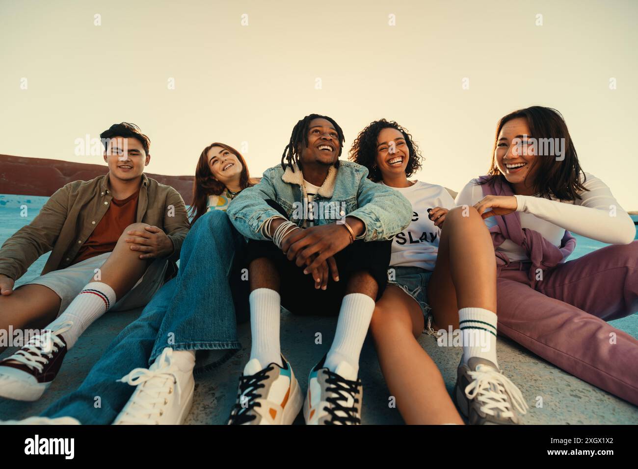Happy group of friends sitting together outdoors, smiling and laughing ...