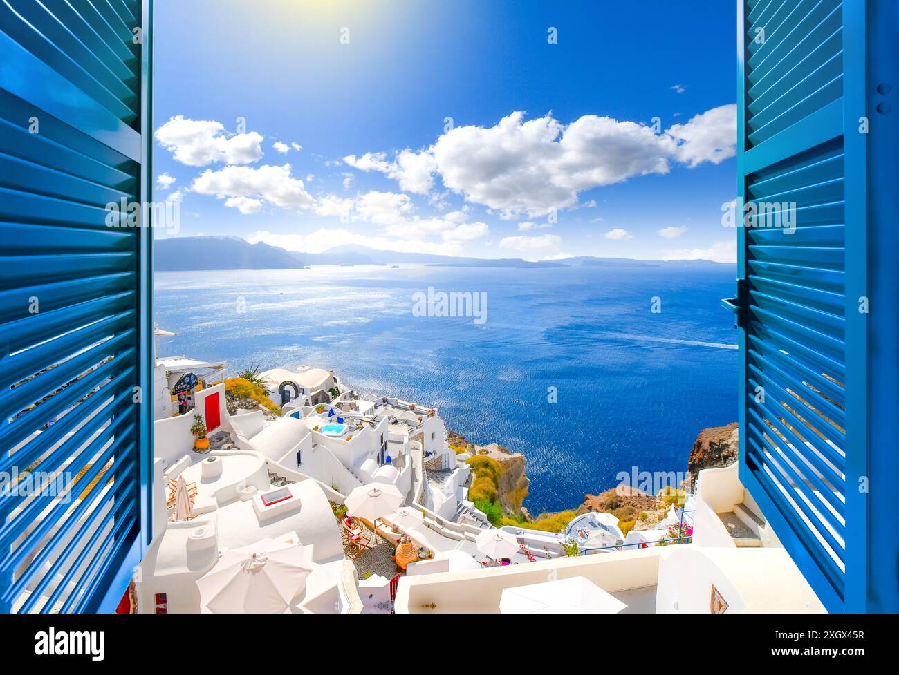 Hillside view through an open window with blue shutters of the caldera ...