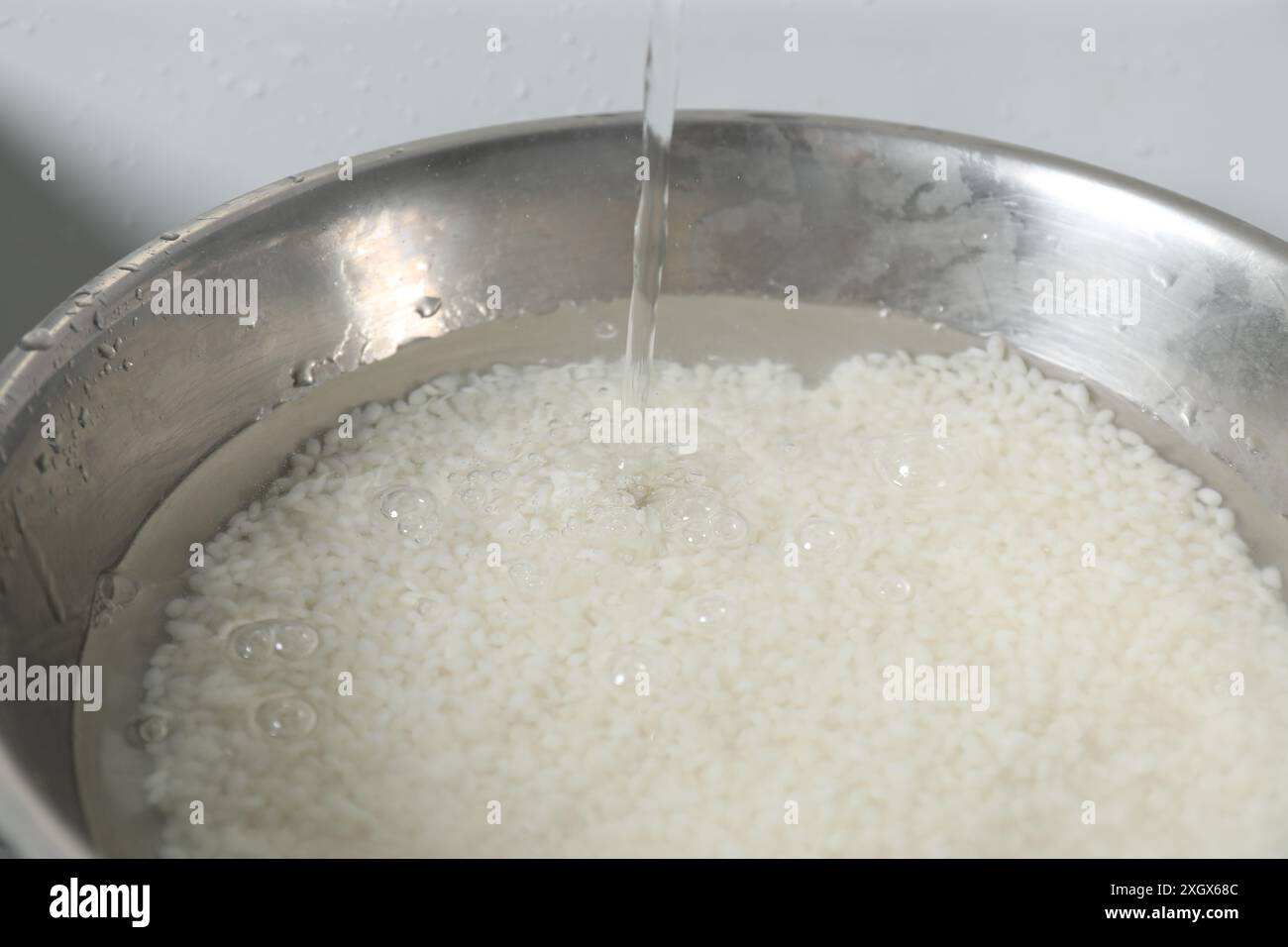 Pouring water into bowl with rice in sink, closeup Stock Photo - Alamy