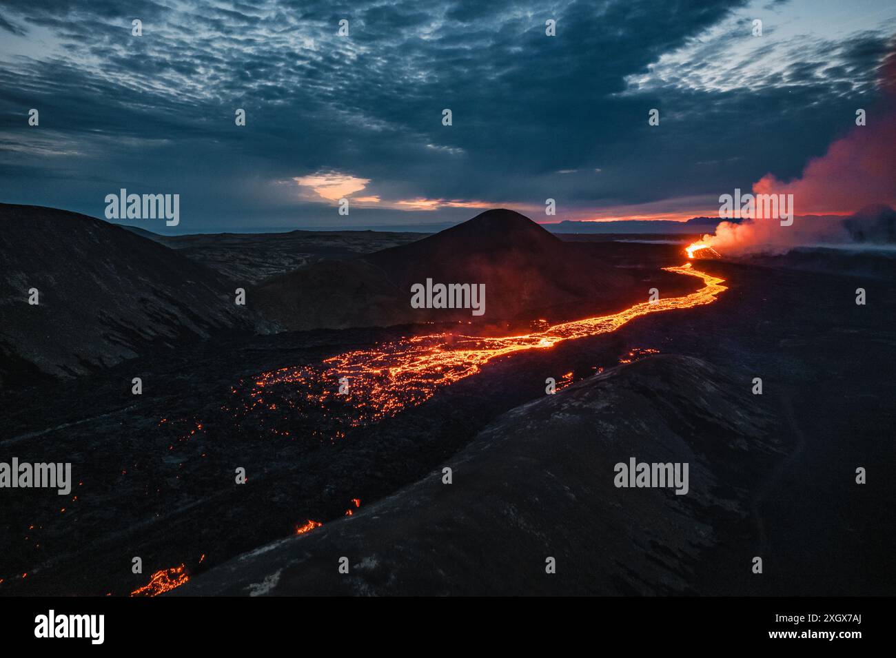 A stunning view of a volcanic eruption with flowing lava during sunset ...