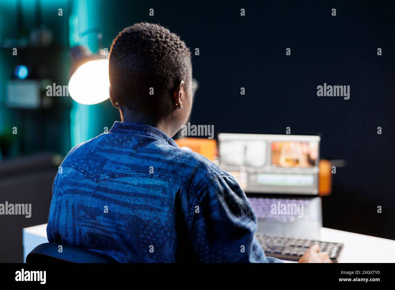 An African American woman edits footage on her laptop at her home ...