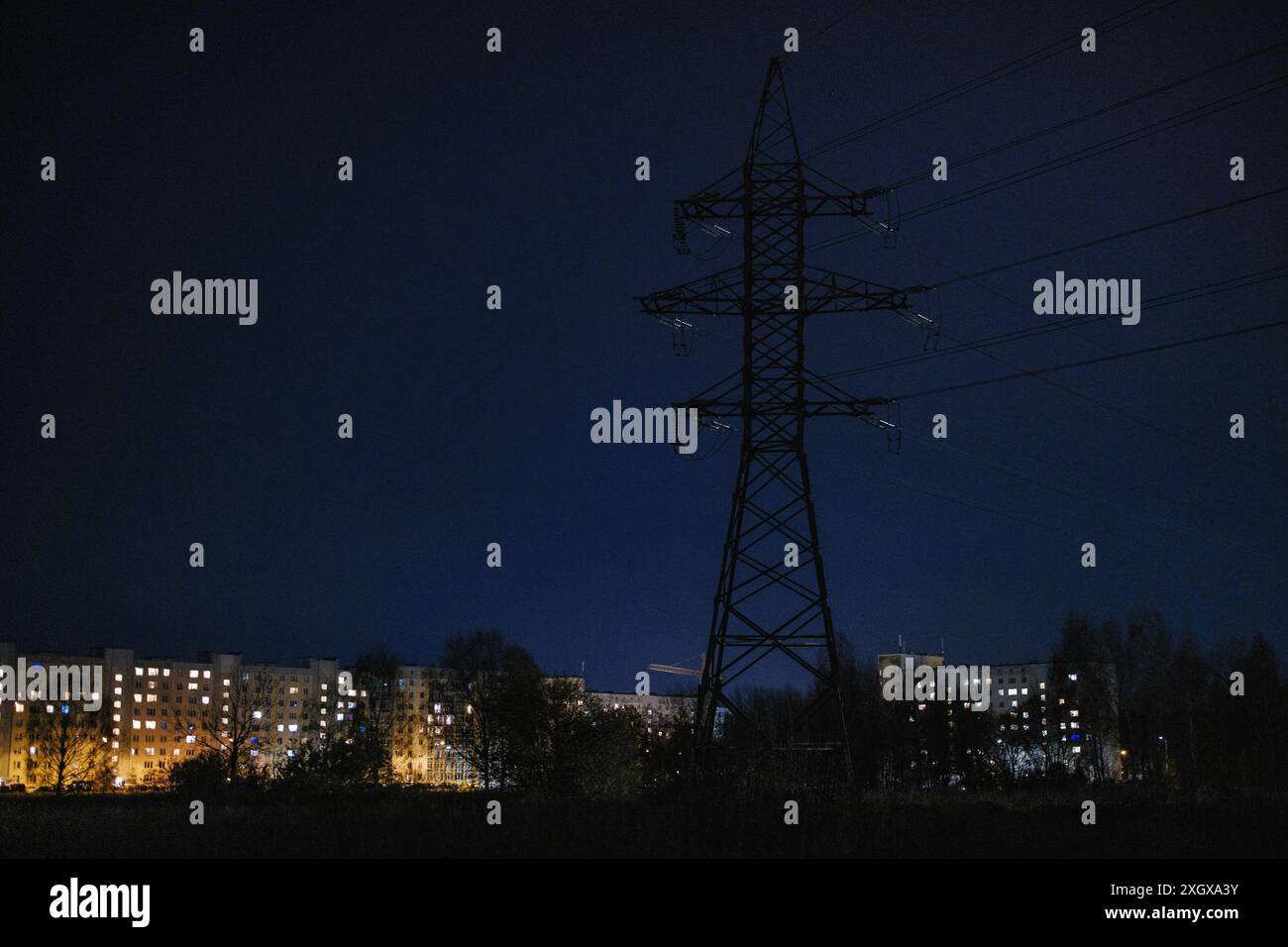 A night view of a transmission tower in a field with apartment ...