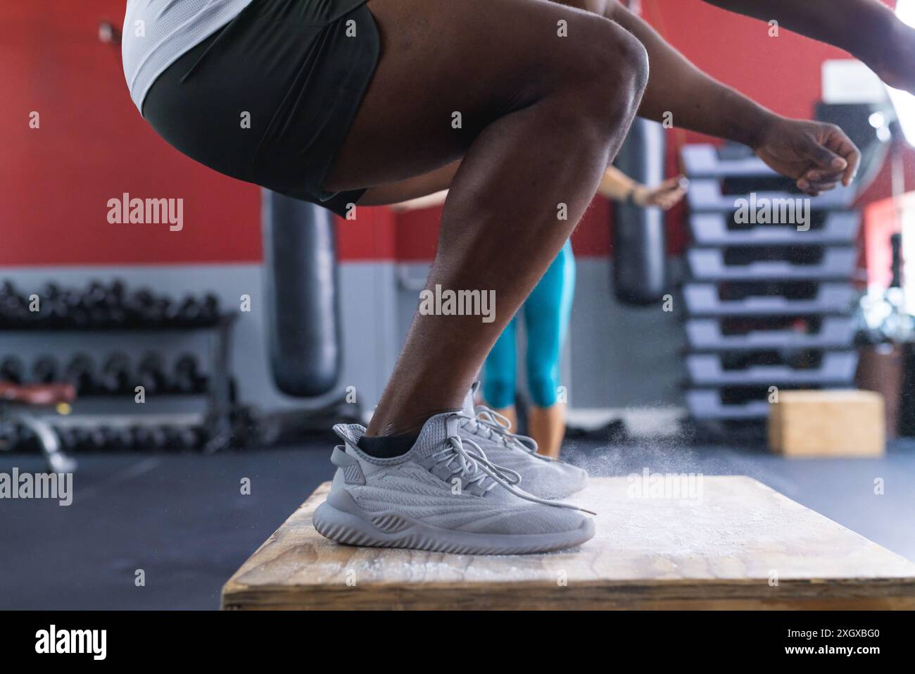 A fit African American man performs a box jump at the gym. His ...