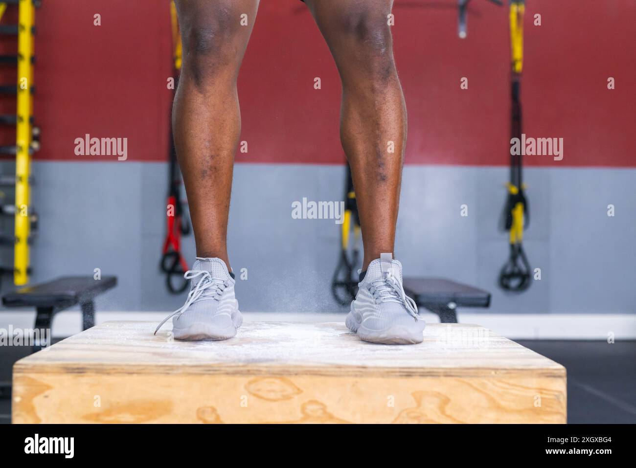 A fit African American man performs a box jump at the gym. His workout ...