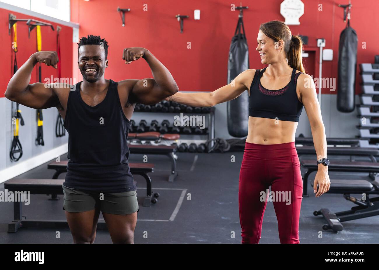 Fit African American man and young Caucasian woman at the gym. They're ...