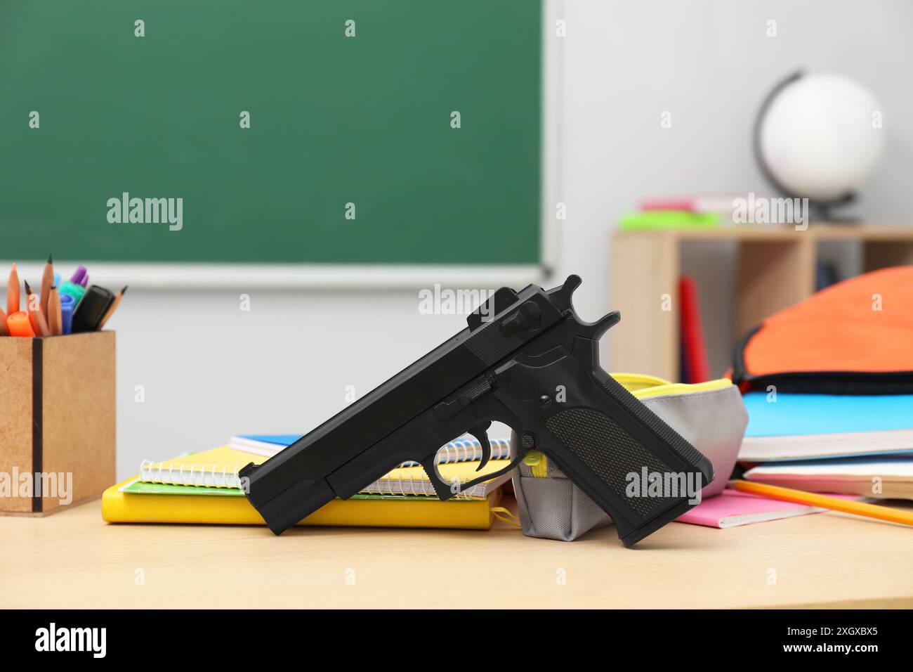 School stationery and gun on desk in classroom Stock Photo - Alamy