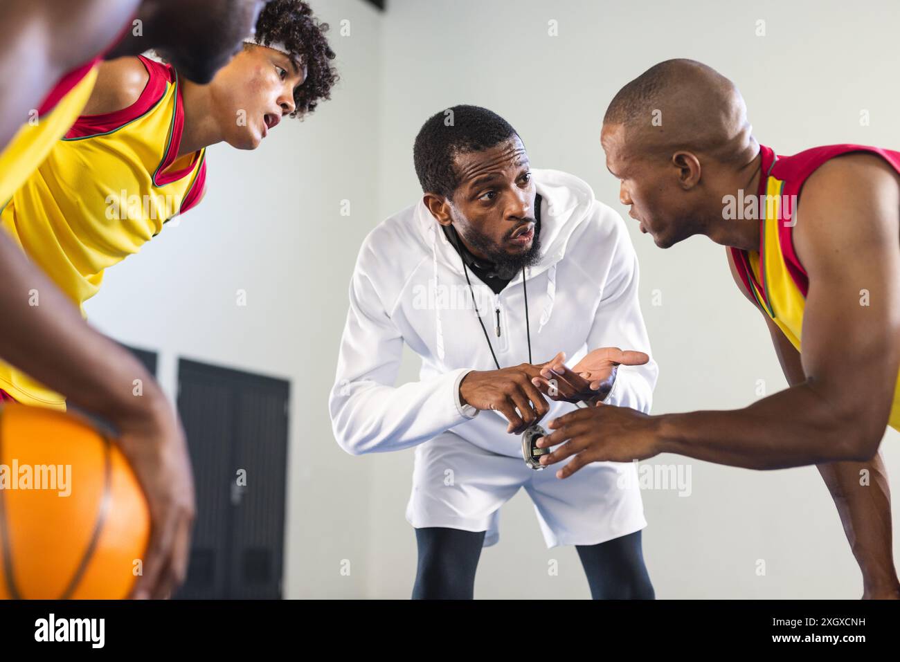 Coach strategizes with basketball players during a timeout, focusing on ...