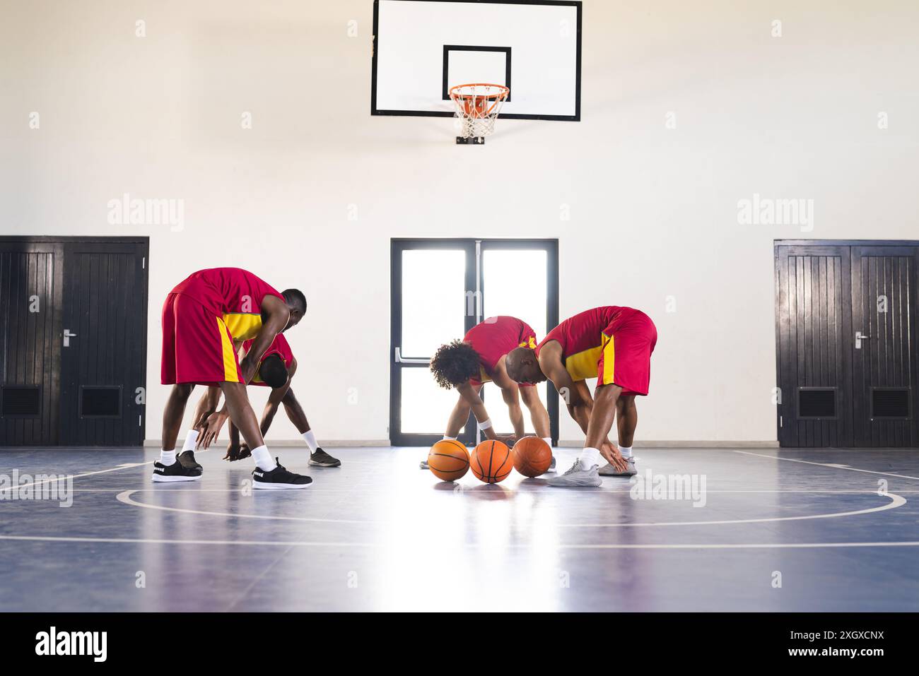 Basketball players prepare for a game in an indoor court. The athletes ...