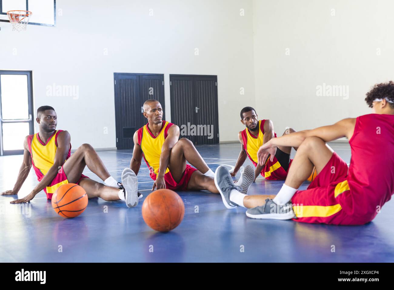 Diverse basketball players rest on the court, embracing both sport and ...