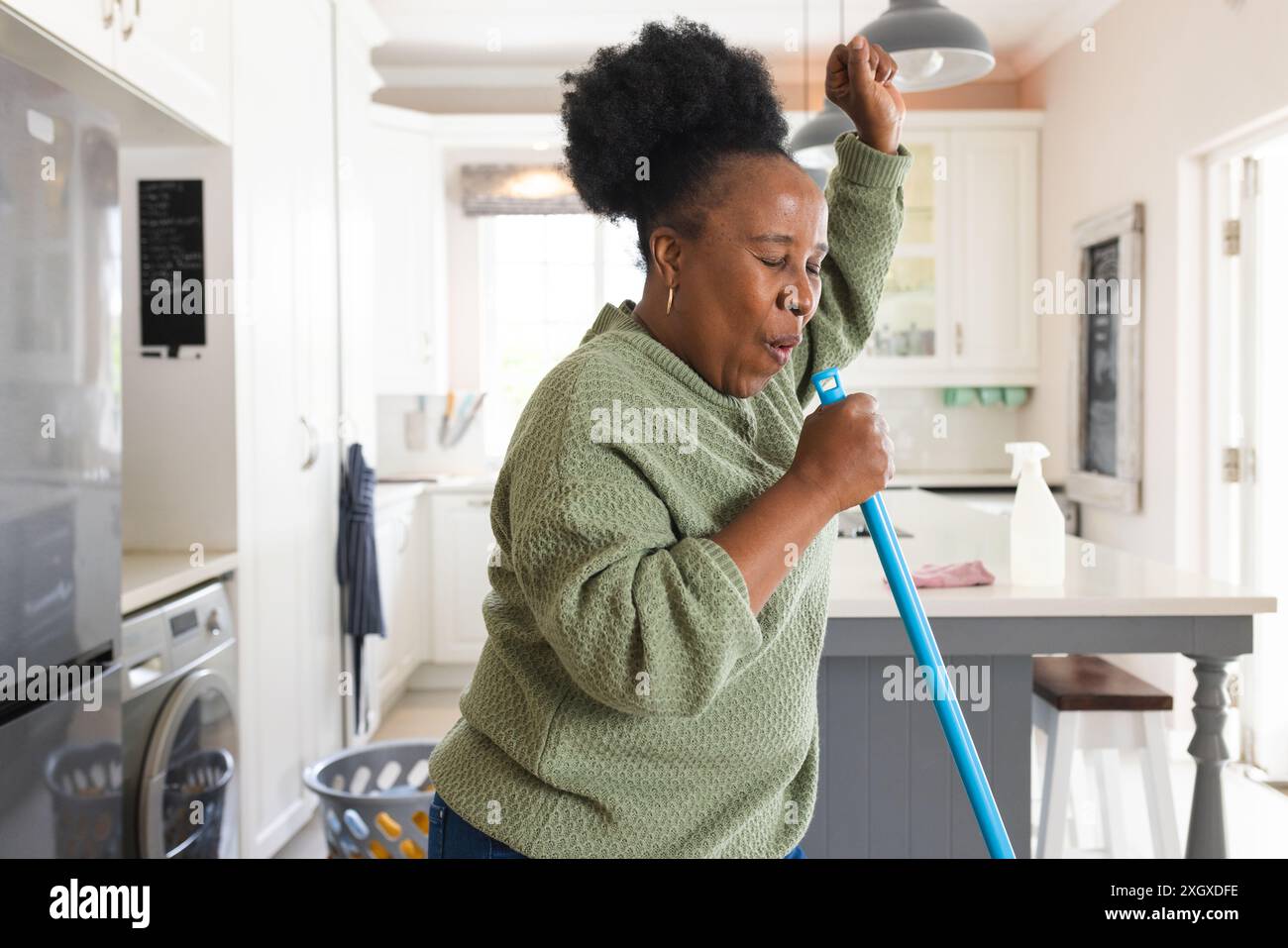 Happy senior african american woman dancing and cleaning floor with mop ...
