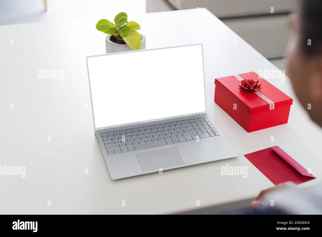 Laptop screen faces the camera on a white desk, with copy space. A red ...