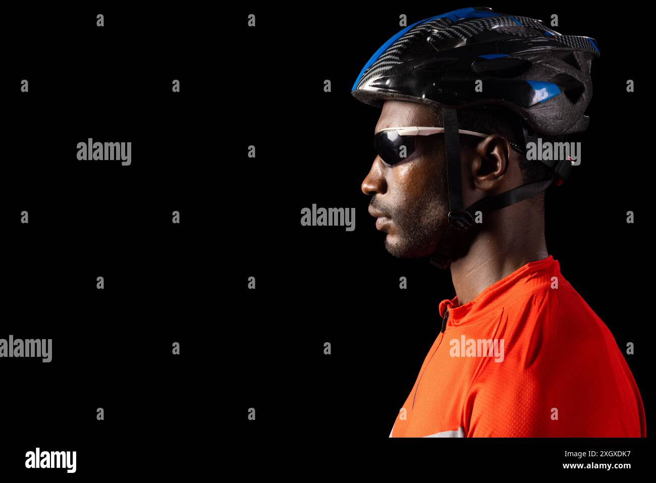 African American man in cycling gear poses confidently on black ...