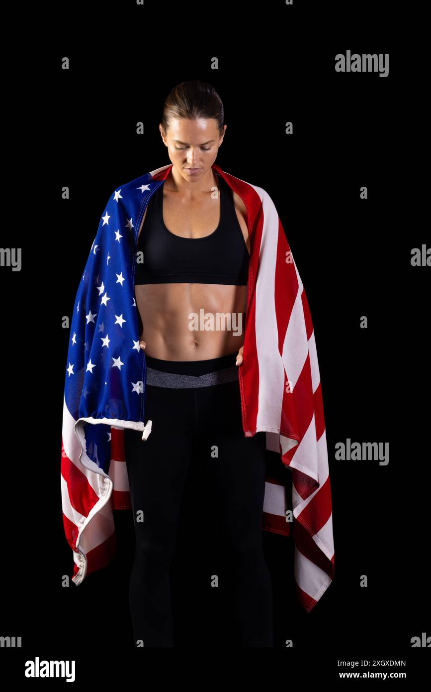 Athletic young Caucasian woman draped in an American flag, with copy ...