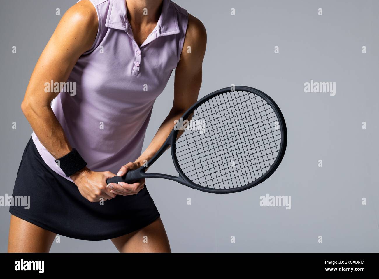 Athlete in tennis attire poses with a racket on a white background ...