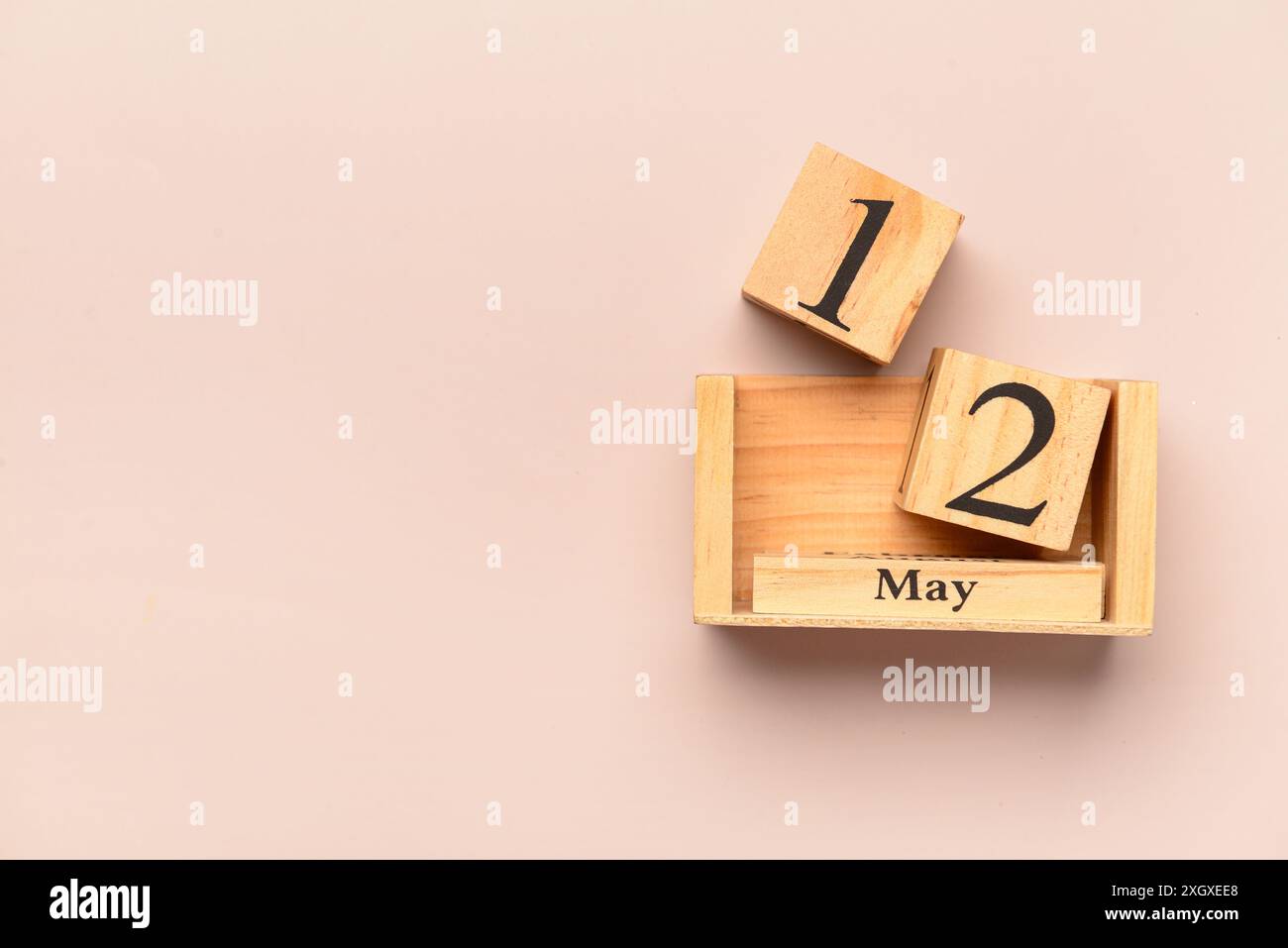 Wooden cube calendar with date 12 MAY on beige background. Top view ...