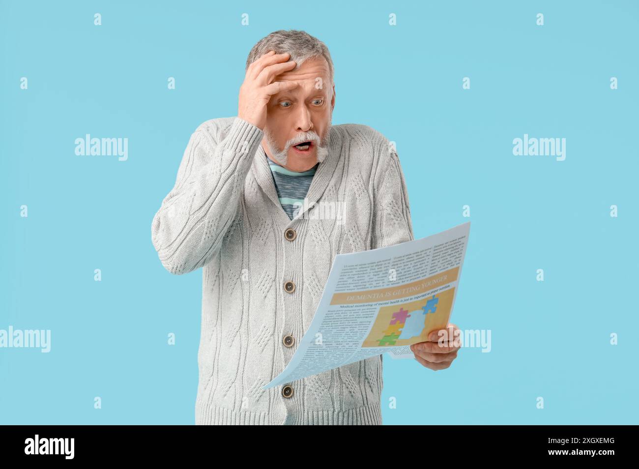 Shocked senior man with newspaper on blue background Stock Photo - Alamy