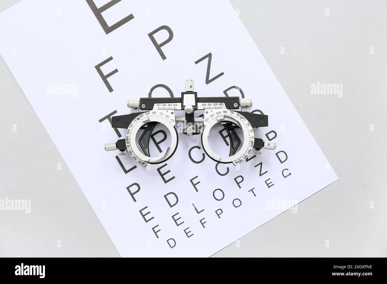 Optical trial frame with eye test chart on white background Stock Photo ...