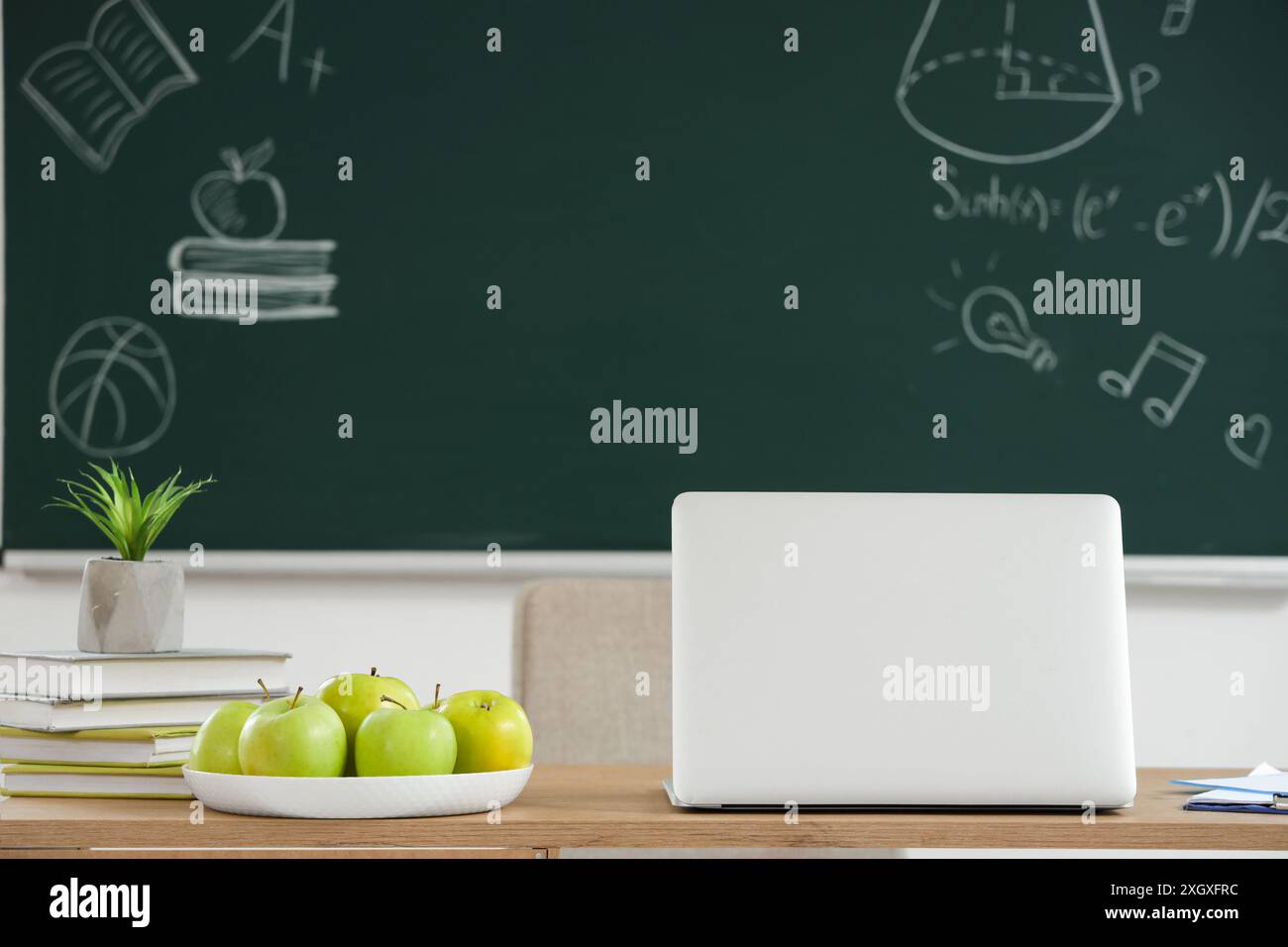 Apples and laptop on teacher's desk in classroom Stock Photo - Alamy