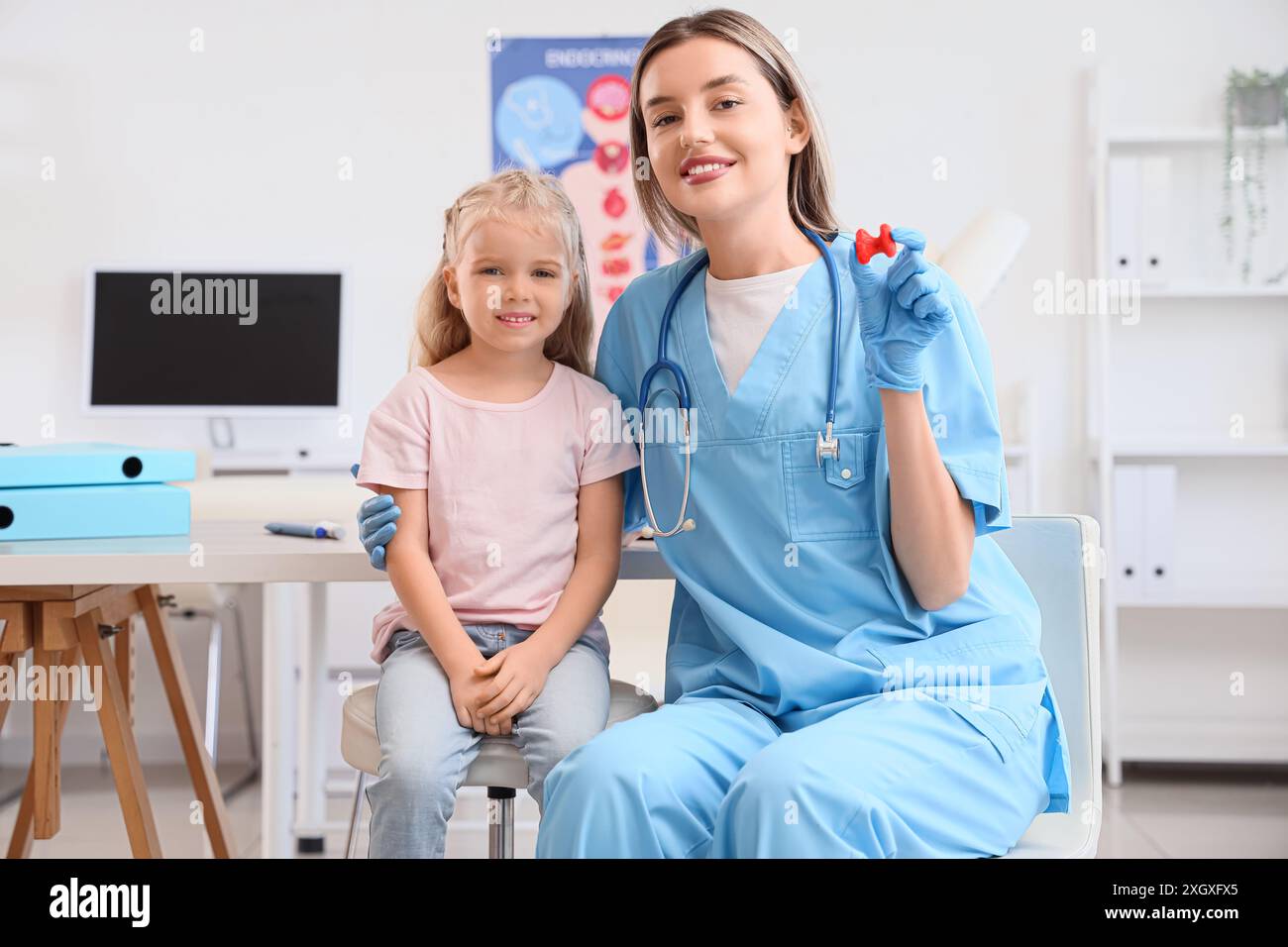 Female endocrinologist with thyroid gland model and little girl in ...