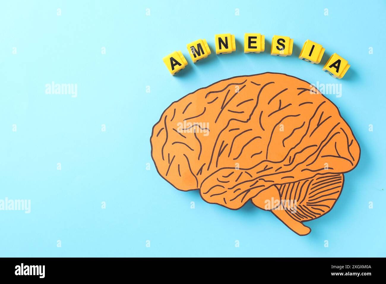 Yellow cubes with word Amnesia and paper cutout of human brain on light ...