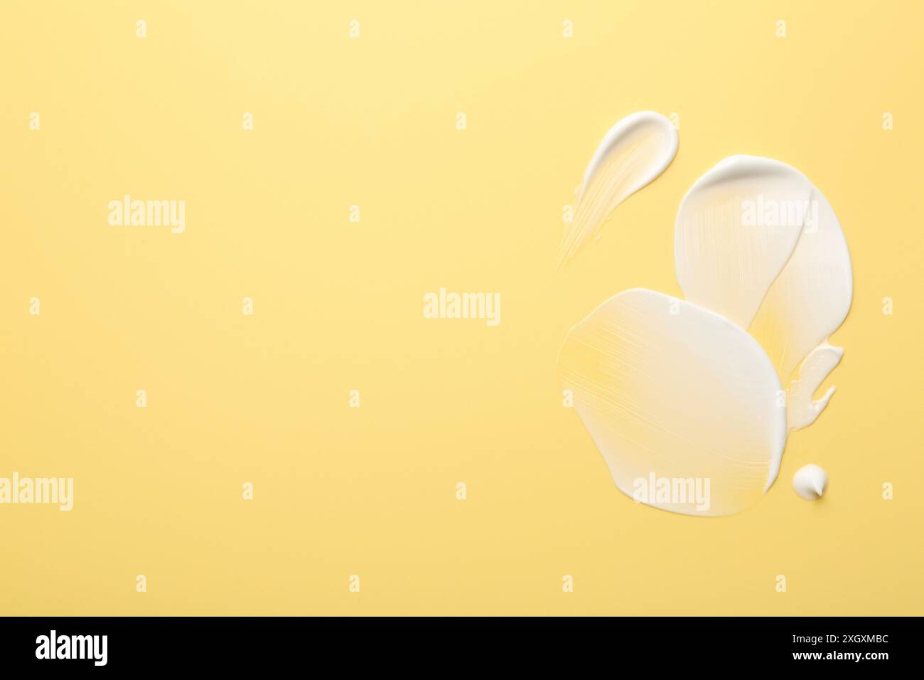 Samples of face cream on yellow background, top view. Space for text ...