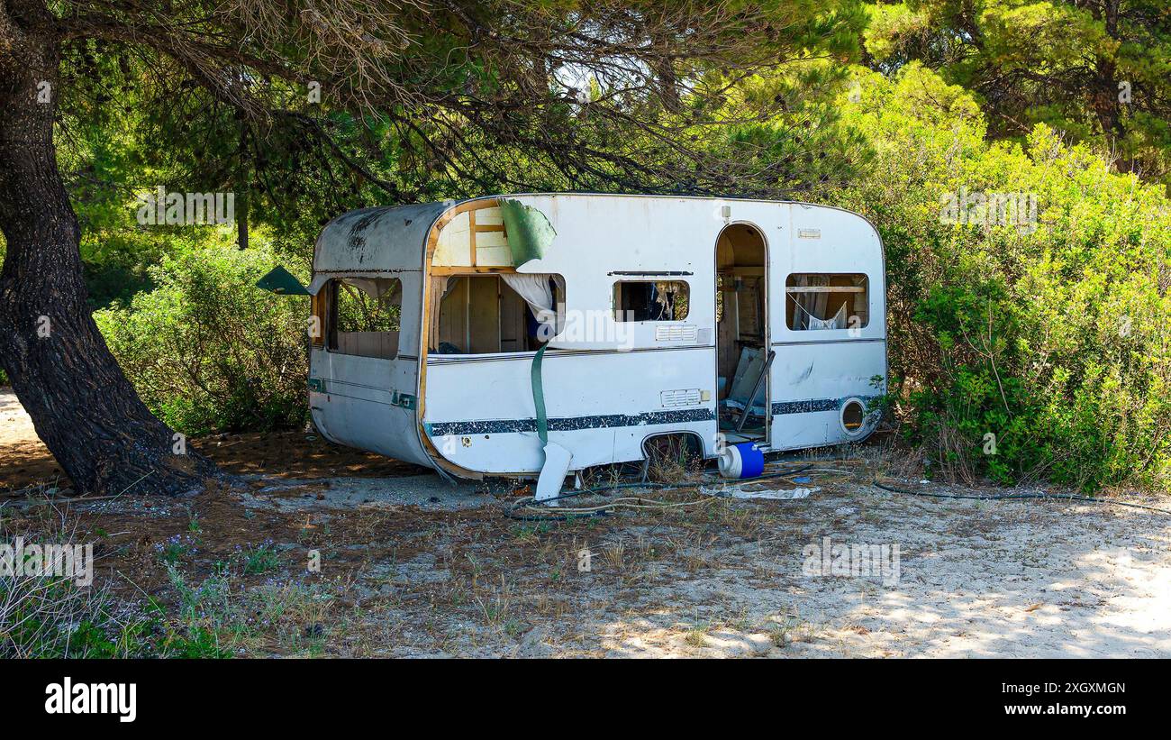 Abandoned and damaged caravan in the shade on a beautiful Mediterranean ...