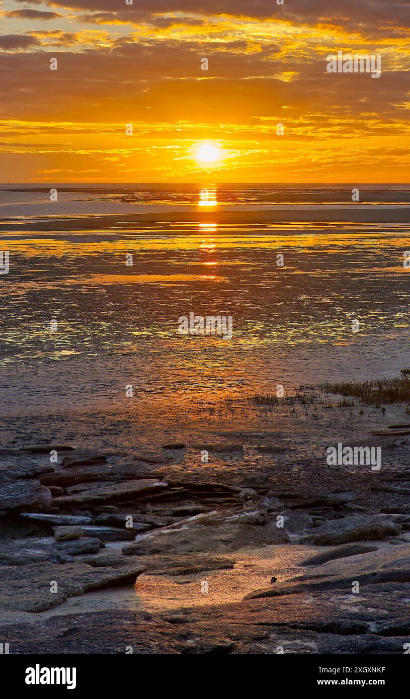 Looking west at orange glow sunset across ocean tidal flats of the ...
