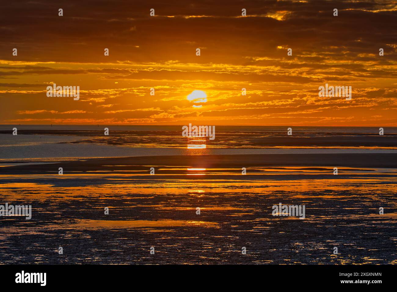 Looking west at orange glow sunset across ocean tidal flats of the ...