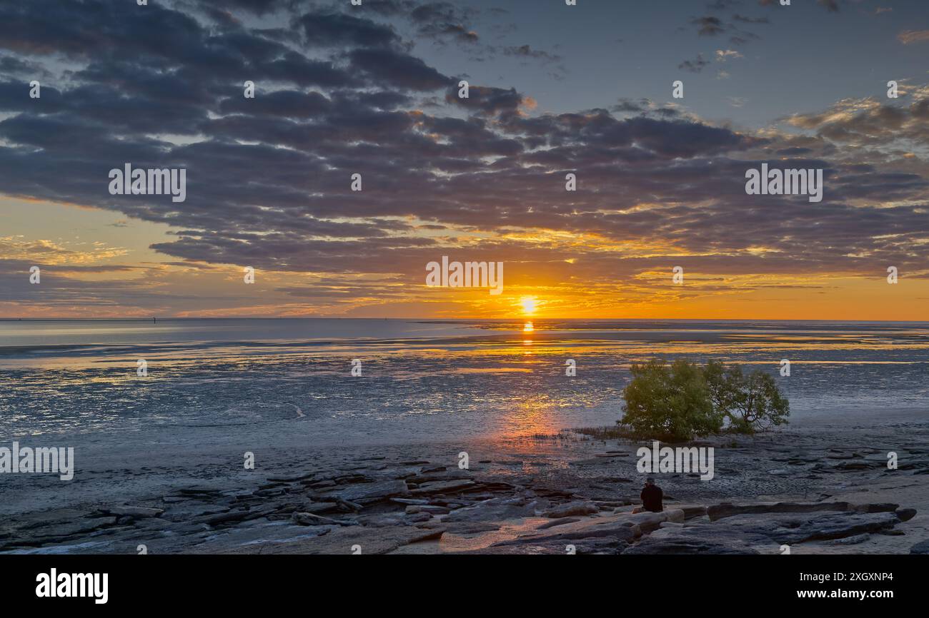 Looking west at orange glow sunset across ocean tidal flats of the ...