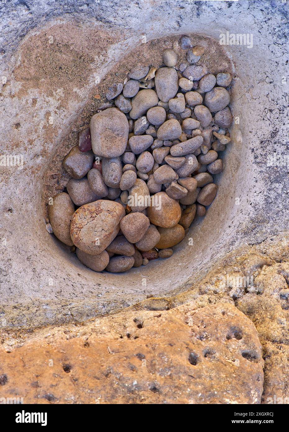 Close up of washed worn polished river rocks pebbles in a hole in river ...