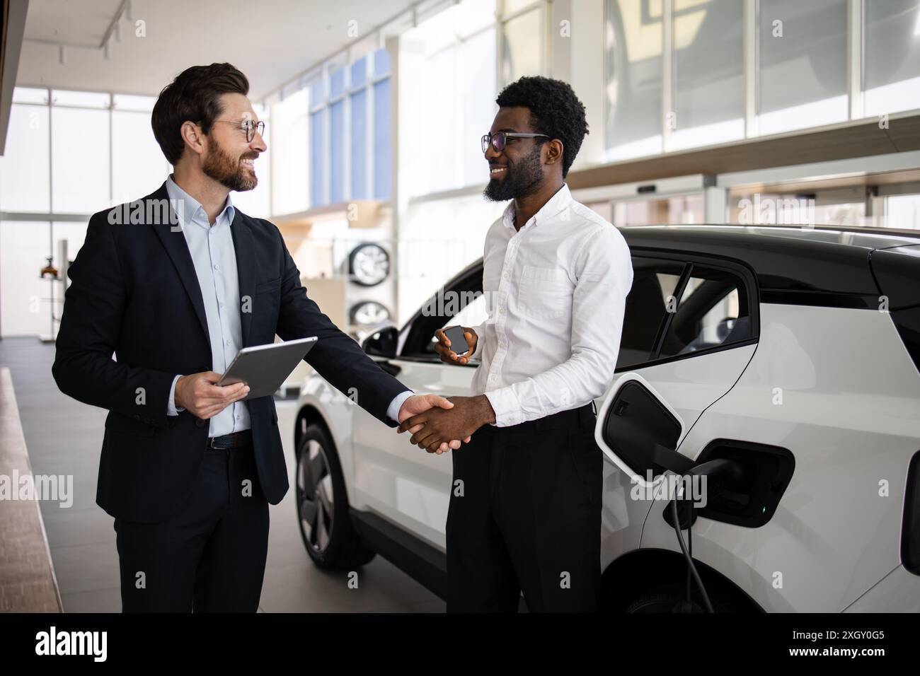 Dealer sells electric SUV to businessman in car dealership Stock Photo ...