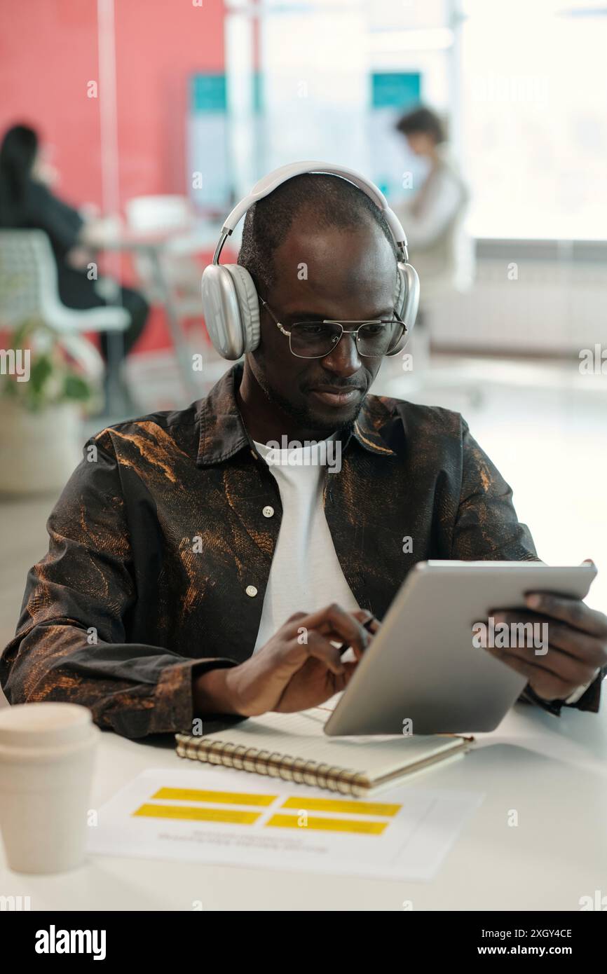 African American man concentrating while working on tablet in modern ...