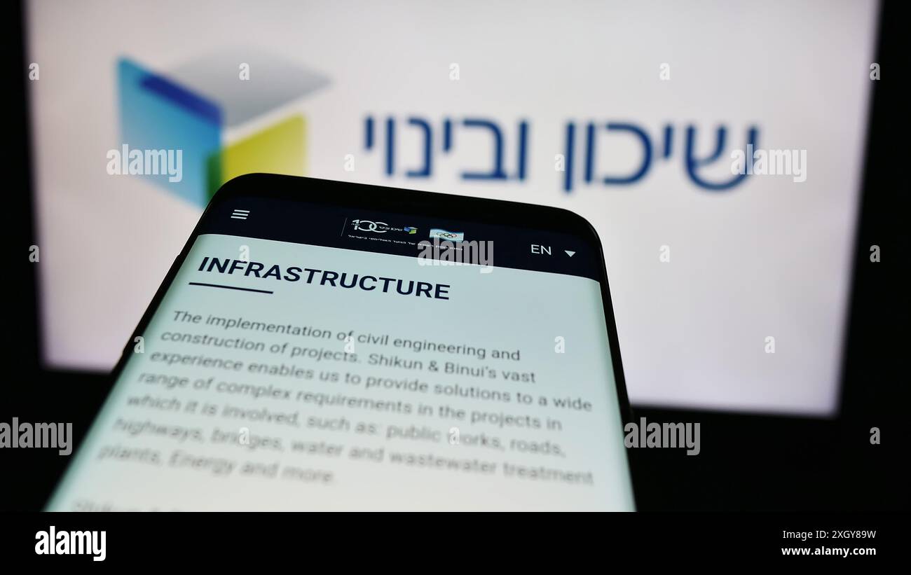 Mobile phone with website of Israeli development company Shikun and Binui in front of business ...