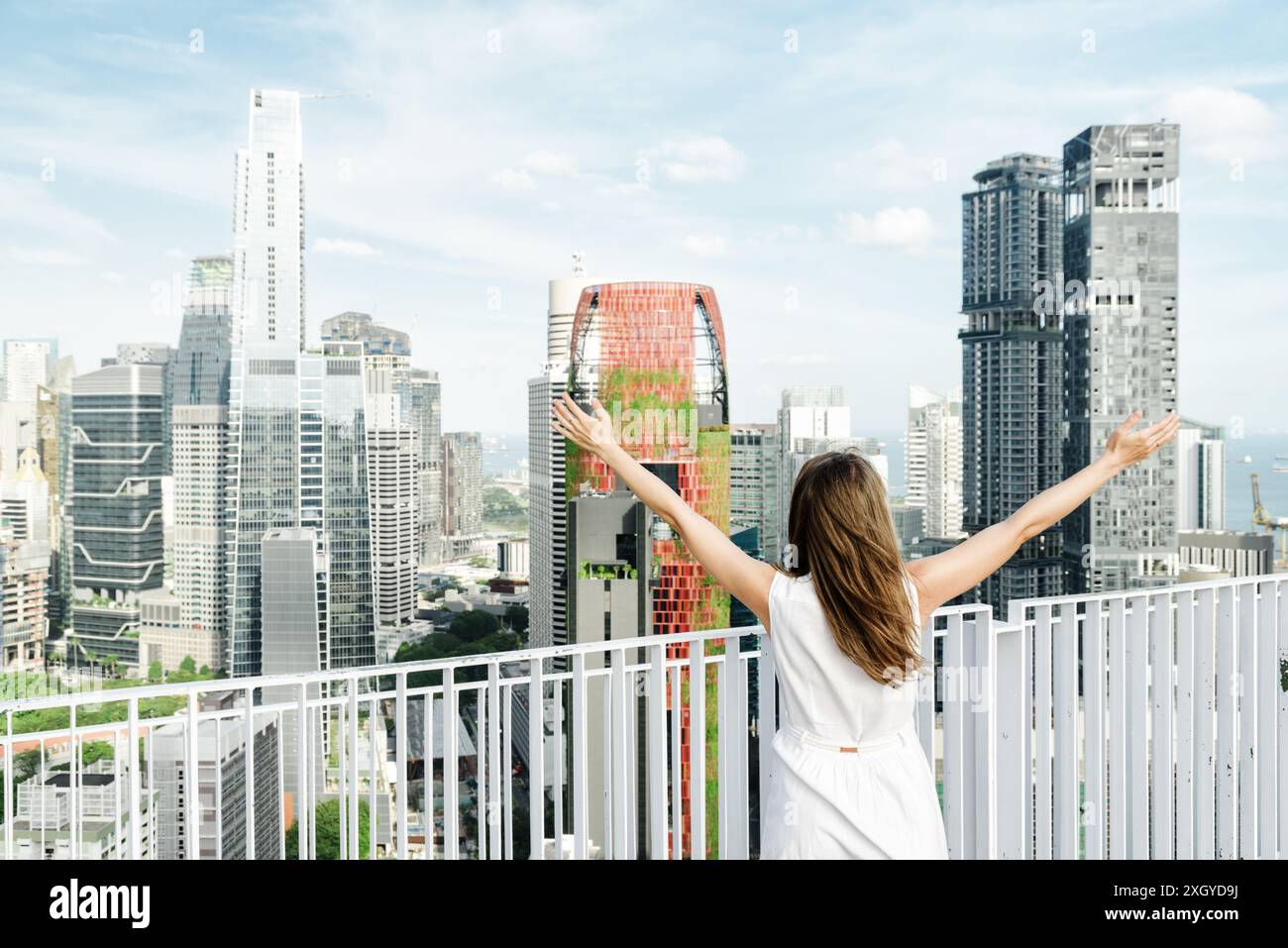 Young woman with raised arms to the sky enjoying beautiful cityscape ...