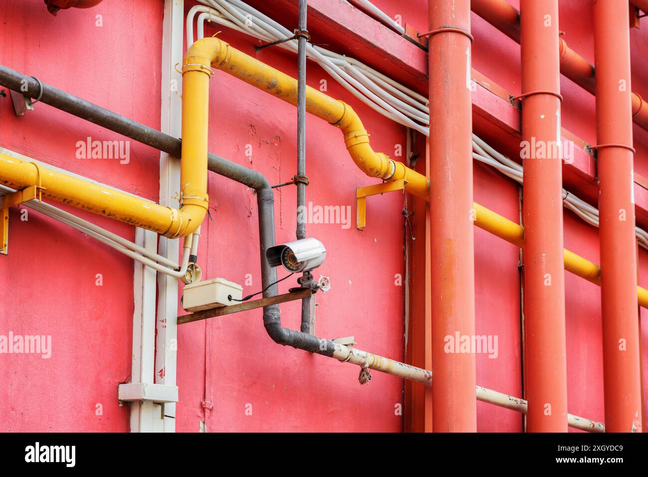 View of pipe system outside a red building. Different pipes and outdoor ...