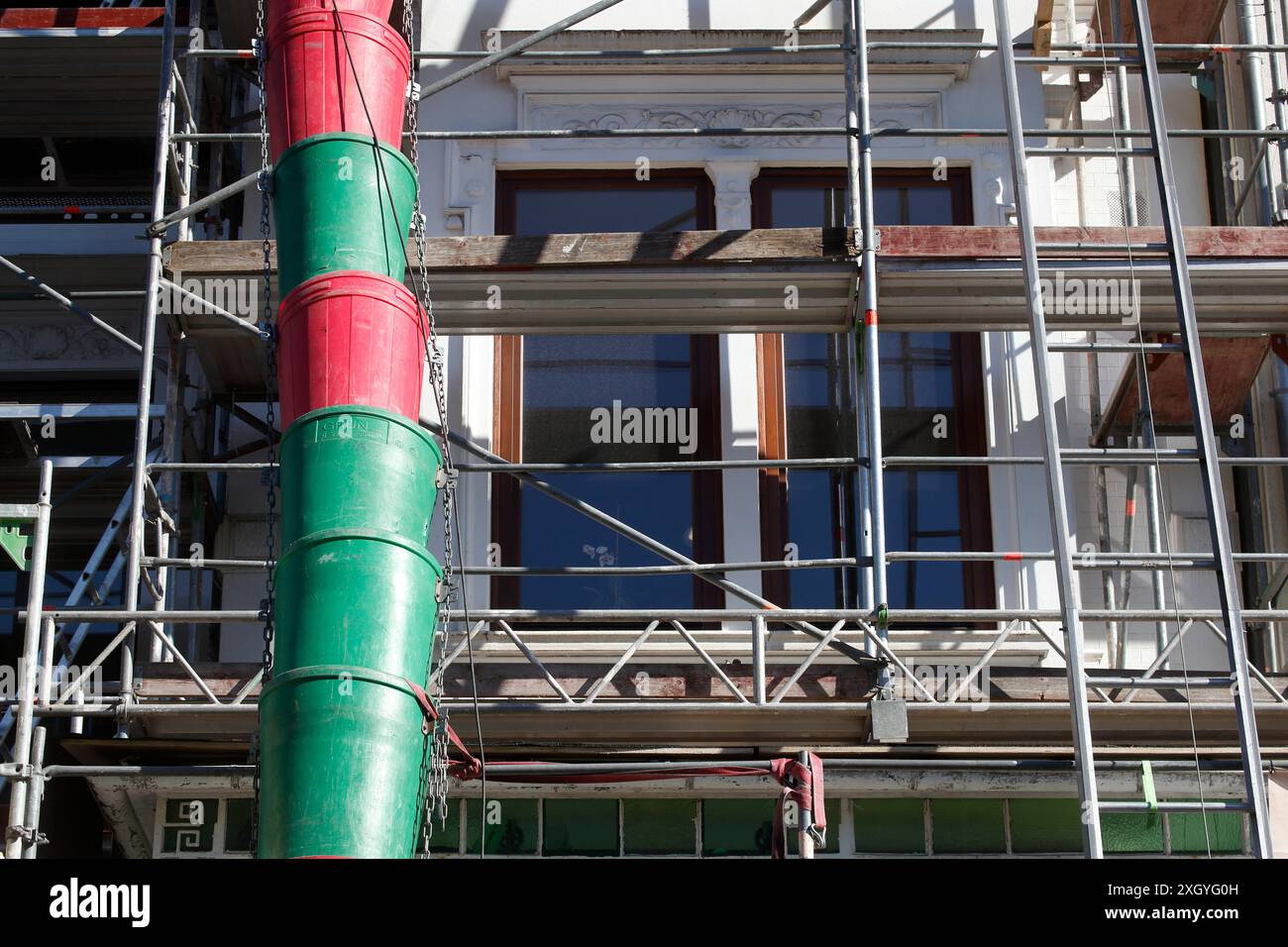 Scaffolding on an old building with colorful plastic buckets, downpipe ...