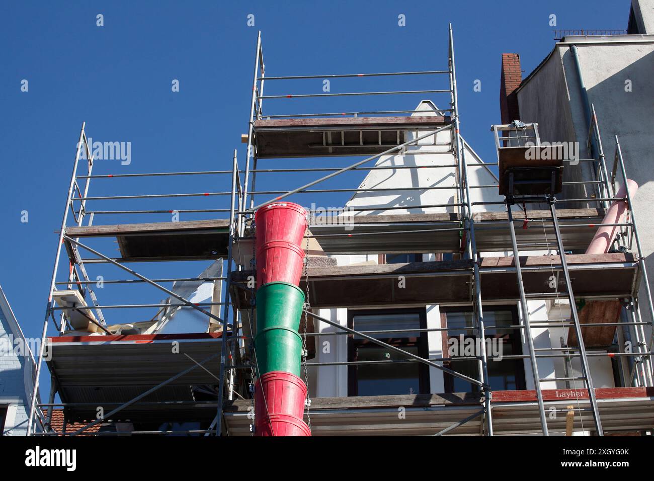 Scaffolding on an old building with colorful plastic buckets, downpipe ...