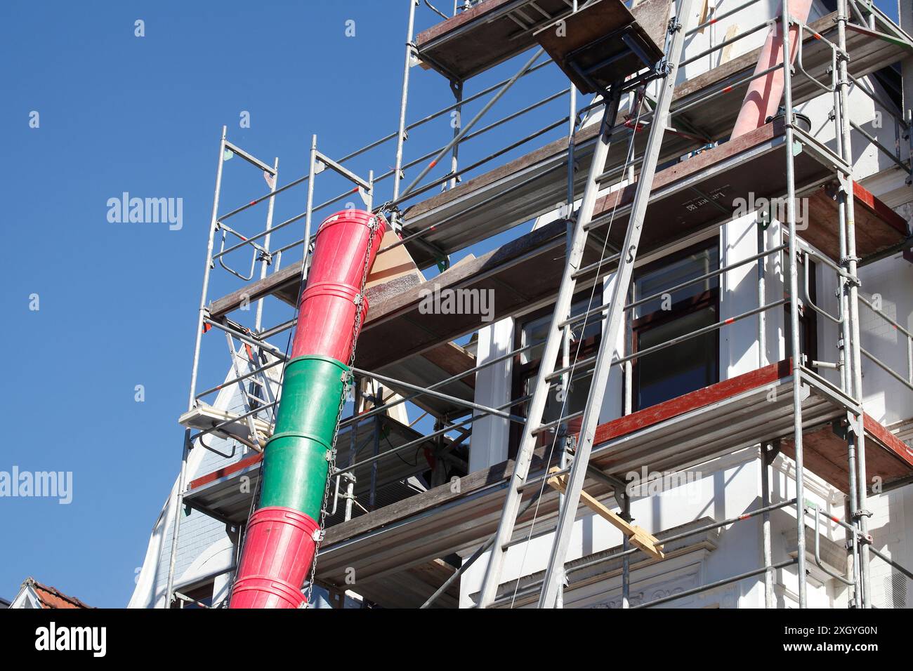 Scaffolding on an old building with colorful plastic buckets, downpipe ...
