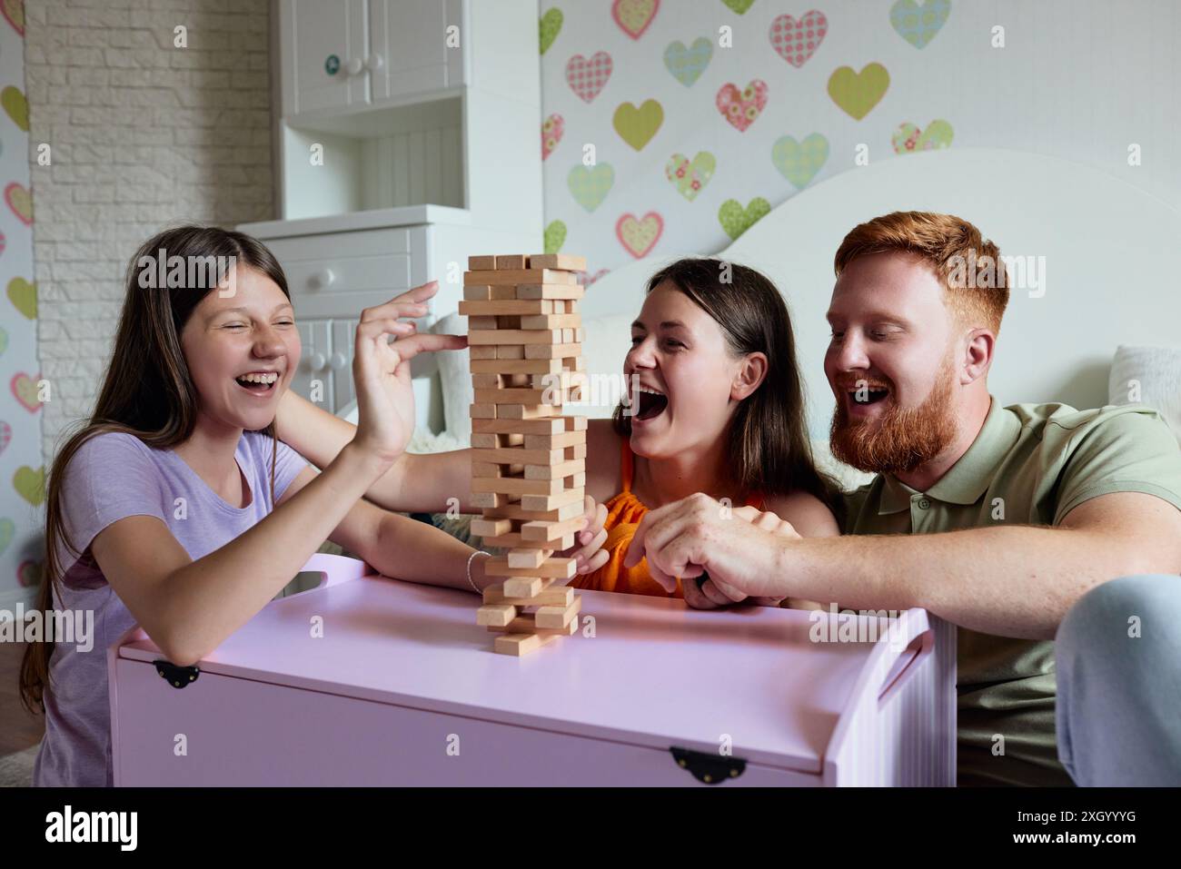 Three people laughing while playing a game of Jenga Stock Photo - Alamy