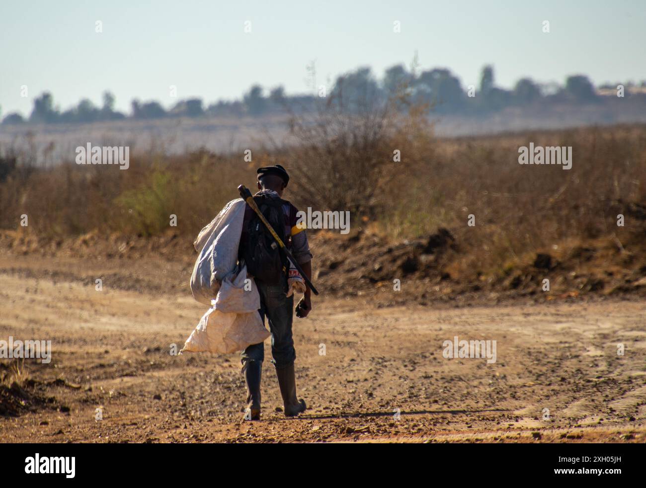 Johannesburg, South Africa - a homeless black man walks on a dirt road ...