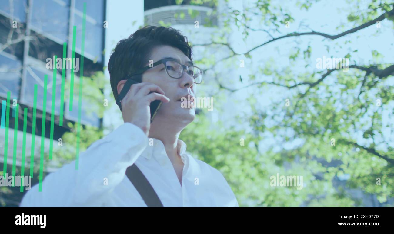 Image of multiple graphs over low angle view of asian man talking on ...