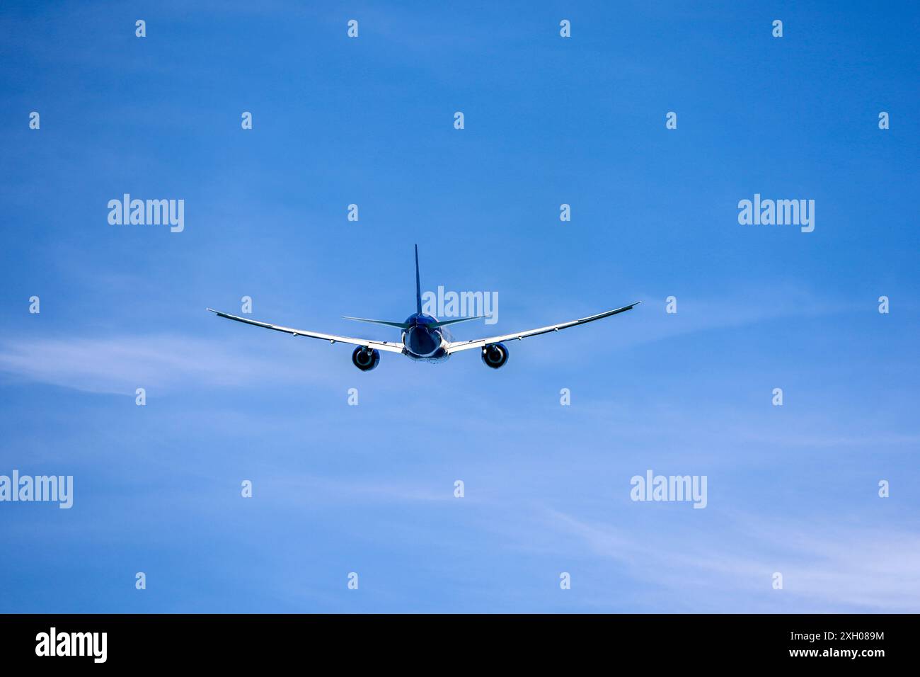 Airplane flying in blue sky, back view. Passenger plane at flight ...