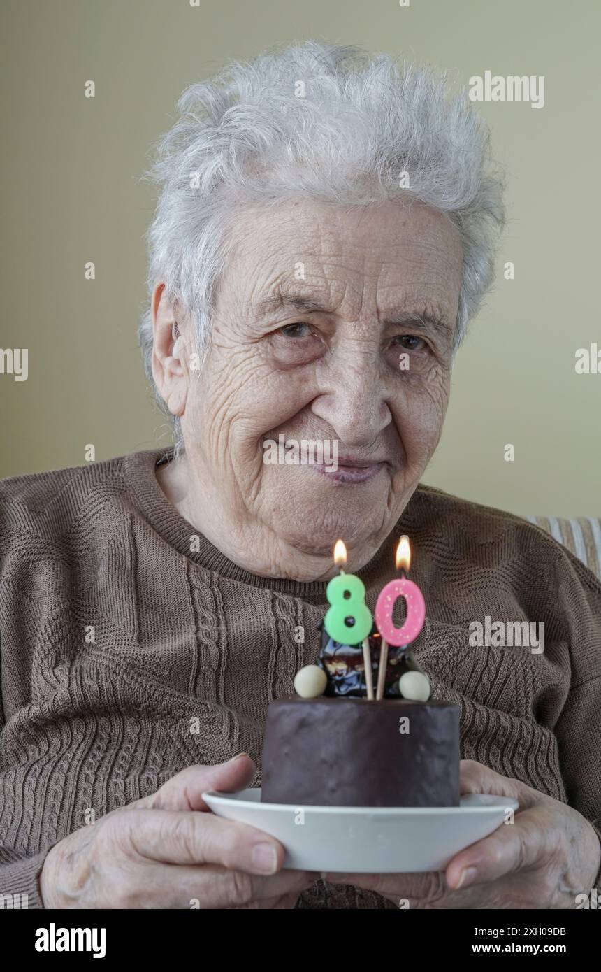 A lovely senior woman holding her birthday cake for age eighty Stock ...