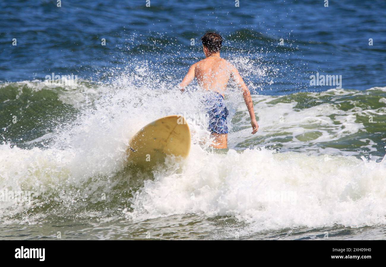 Close up of a teenage boy falling off of his surfboard into the ...