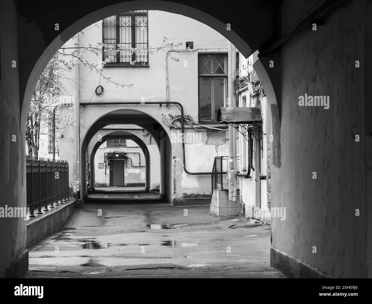 Monochromatic image showcasing an old urban alleyway with archways and ...