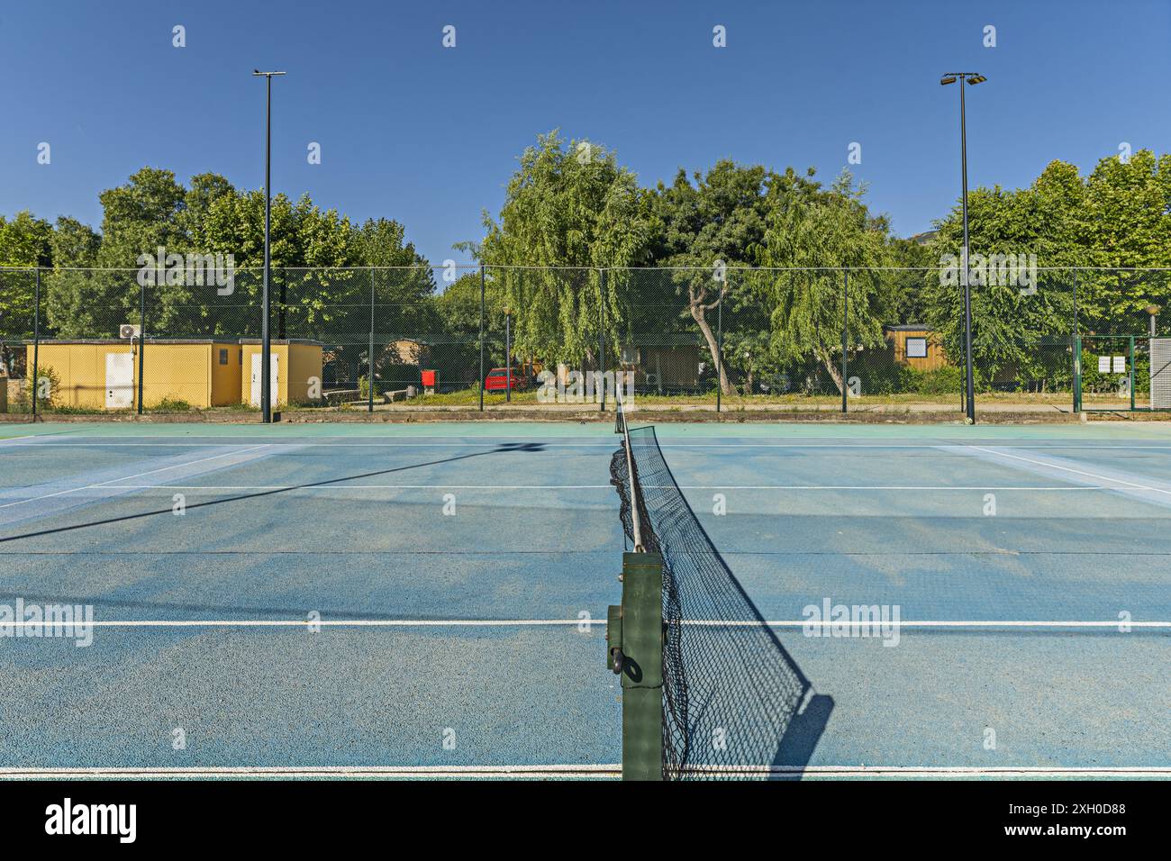 setting of a tennis and pelota court, with the sun shining softly on ...